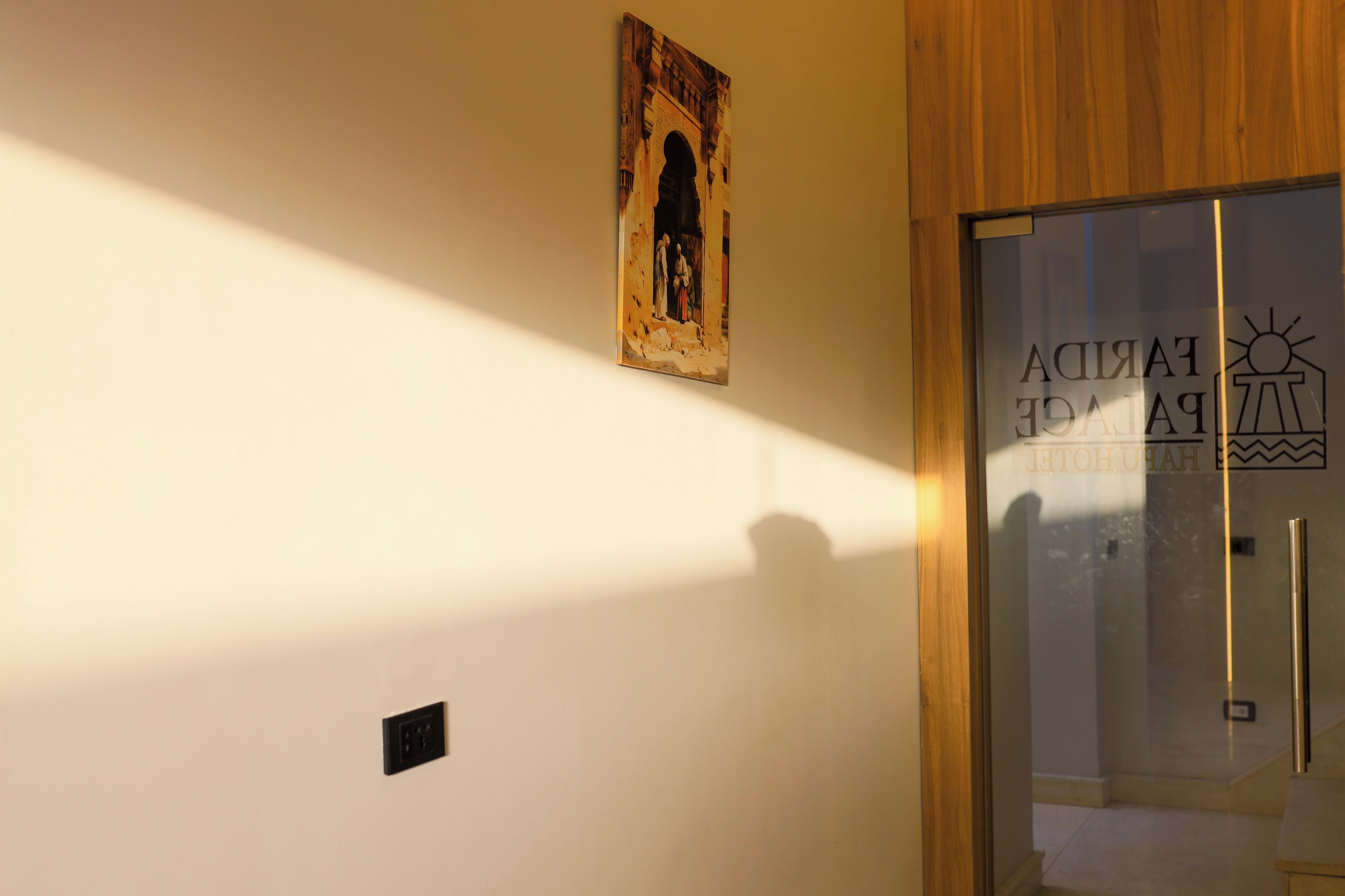 Quarto de hotel com porta de vidro, uma obra de arte na parede e um interruptor de luz visível.