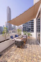 Terraço no telhado com área de estar, plantas em vasos e vista para o horizonte da cidade.