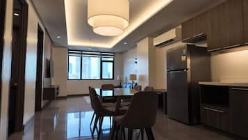 Cozinha moderna com geladeira embutida, área de refeições com mesa e cadeiras, e vista para prédios altos pela janela.