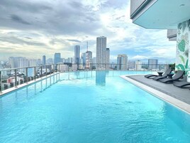 Piscina no terraço com vista para o horizonte urbano, espreguiçadeiras e design arquitetônico moderno.