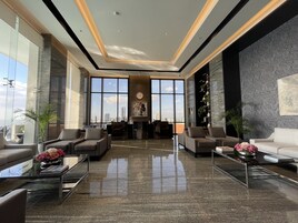Um lobby espaçoso com teto alto, grandes janelas com vista para a cidade e móveis modernos.