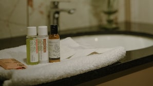 Uma pia de banheiro com produtos de higiene e uma toalha.