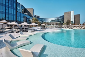 Um hotel moderno com uma piscina grande, espreguiçadeiras e guarda-sóis.