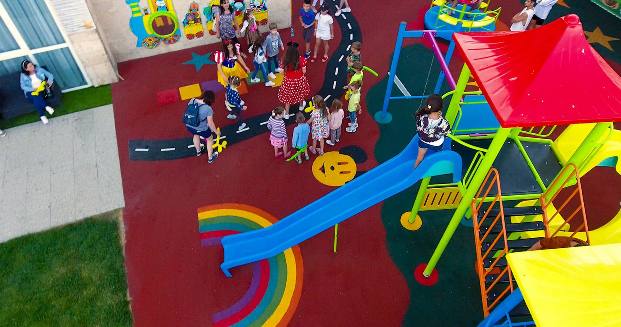Um parquinho com escorrega, estruturas de escalada e uma área de lazer colorida.