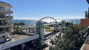 Um edifício moderno com fachada de vidro, uma passarela e vista para o mar.