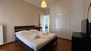 Quarto com cama grande, mesa de cabeceira, televisão e guarda-roupa.