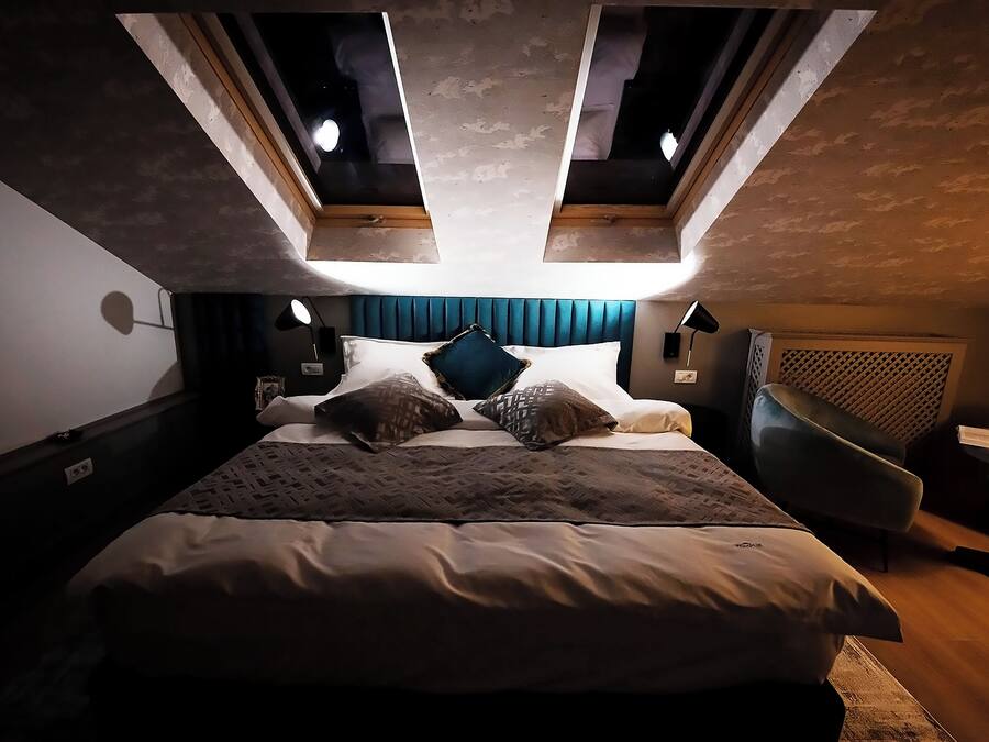 Quarto com cama grande, cabeceira com design vazado e claraboia.