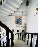 Uma escadaria com paredes brancas, uma pintura de vaca azul e um pequeno objeto decorativo na parede.