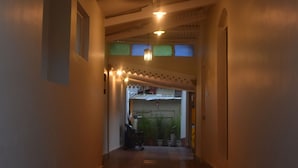 Um corredor com piso de azulejos, vigas de madeira no teto e luminárias pendentes.