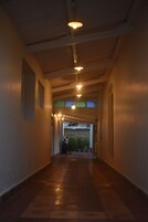 Um corredor com piso de azulejos, vigas de madeira no teto e luminárias pendentes.