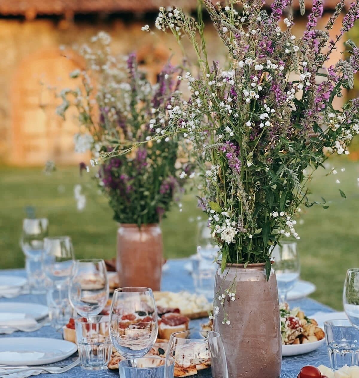 Mesa posta para refeição, com vasos de flores e copos de água.
