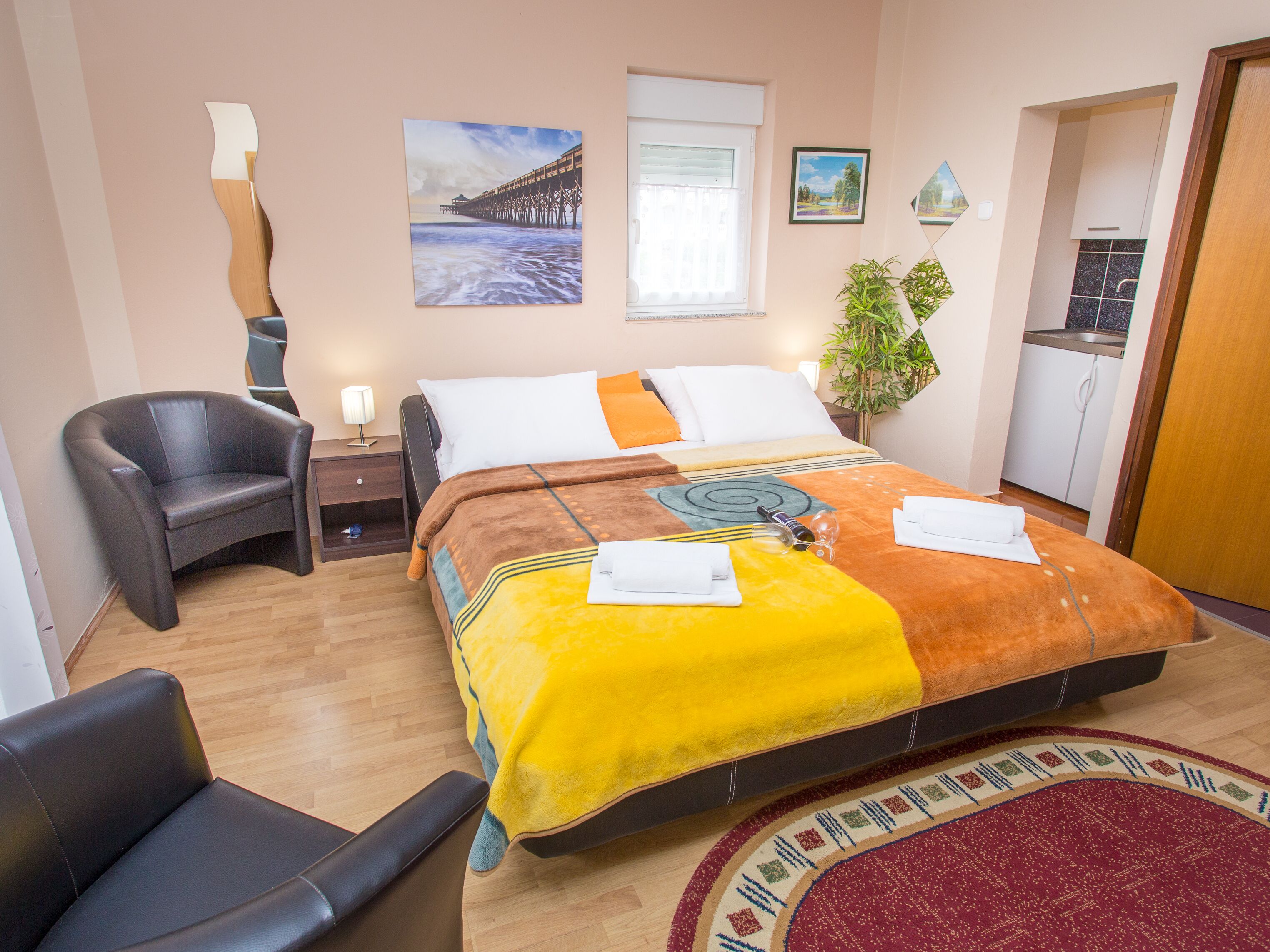 Quarto de hotel com cama, uma cadeira, uma escrivaninha e janela.