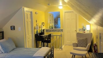 Um quarto de sótão aconchegante com duas camas, uma escrivaninha e uma cadeira.