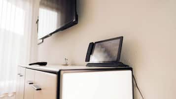Uma escrivaninha com um laptop, um controle remoto e uma pequena estatueta.