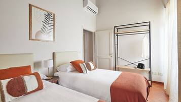 Quarto de hotel com duas camas, guarda-roupa, espelho e ar condicionado fixado na parede.