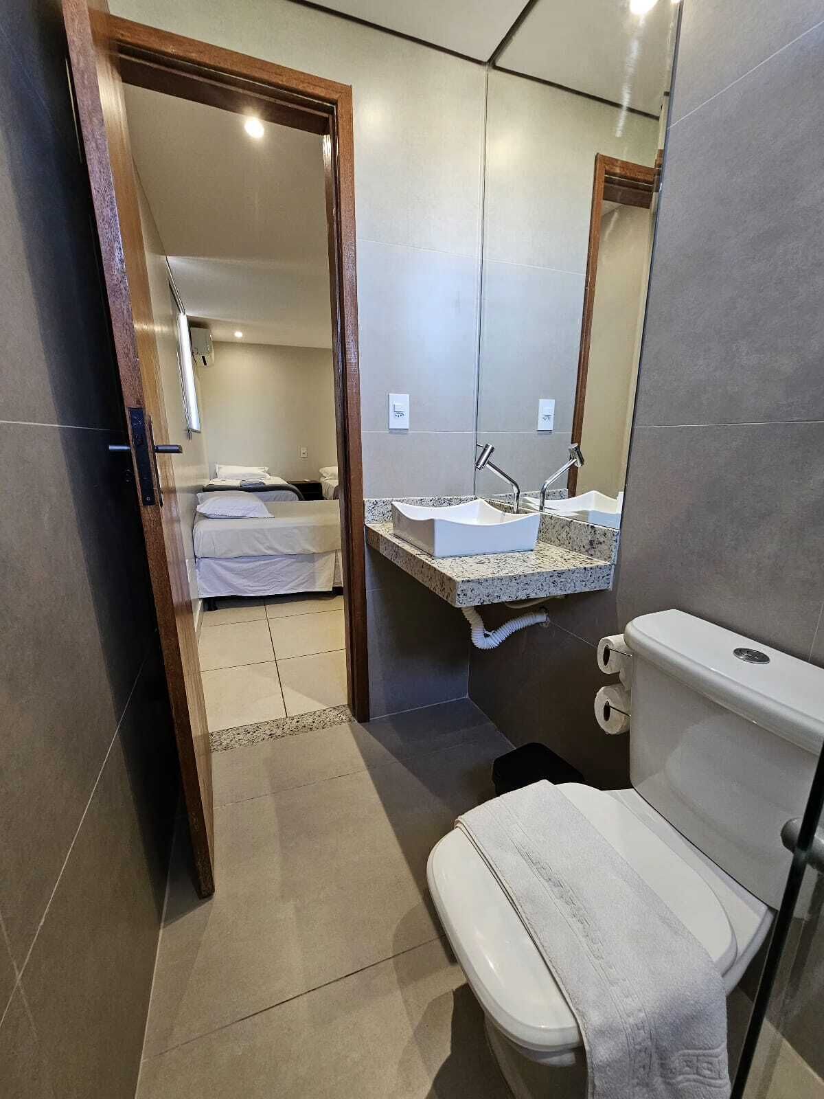 Uma casa de banho de hotel compacta, com sanita, lavatório e espaço de duche.