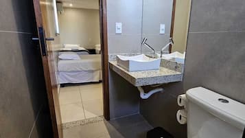 Uma casa de banho de hotel compacta, com sanita, lavatório e espaço de duche.