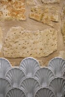 Paredes de pedra com superfície texturizada e fileiras de azulejos cinzentos com bordas recortadas em primeiro plano.
