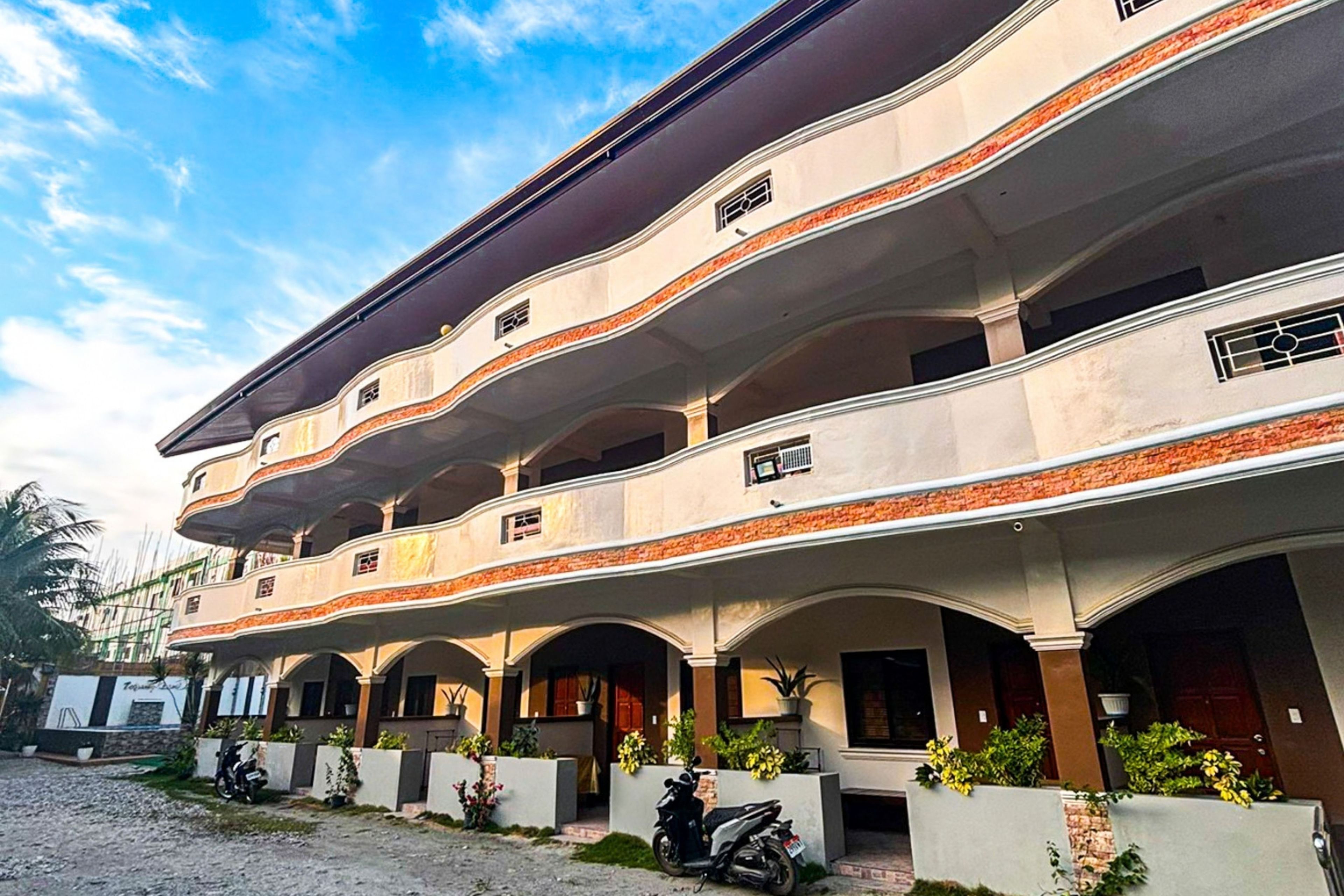 Um edifício de vários andares com telhado plano, varandas e uma série de janelas.