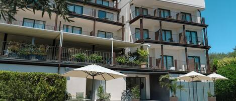 Hotel com vários andares, área de estar externa e vasos de plantas.