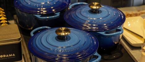 Três panelas de ferro fundido esmaltadas em azul com tampas sobre uma bancada de cozinha.