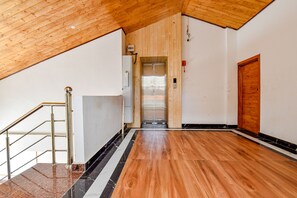 Um interior espaçoso com teto de madeira, piso de madeira polida, escada de metal e porta de madeira.