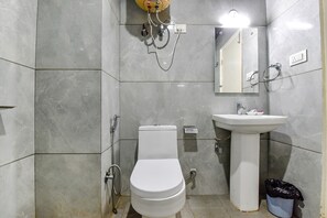 Casa de banho com sanita, lavatório e espelho.