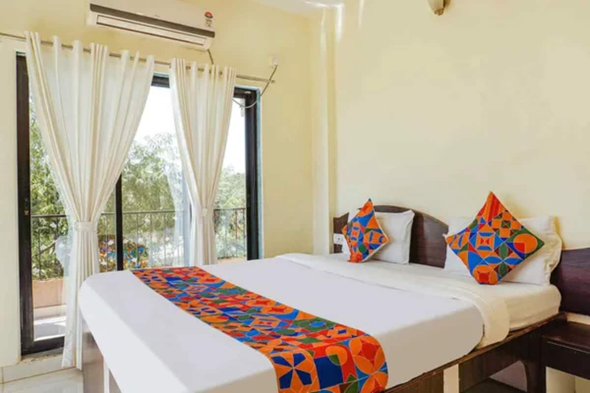 Quarto de hotel com cama, cortinas, janela e varanda.