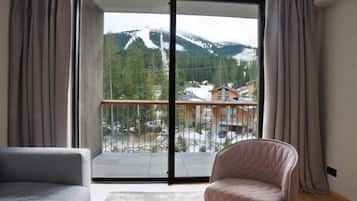 Quarto moderno com uma grande porta de correr de vidro que dá para uma varanda com vista para as montanhas.
