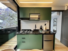 Uma cozinha moderna com armários verdes, uma geladeira de aço inoxidável e um micro-ondas.
