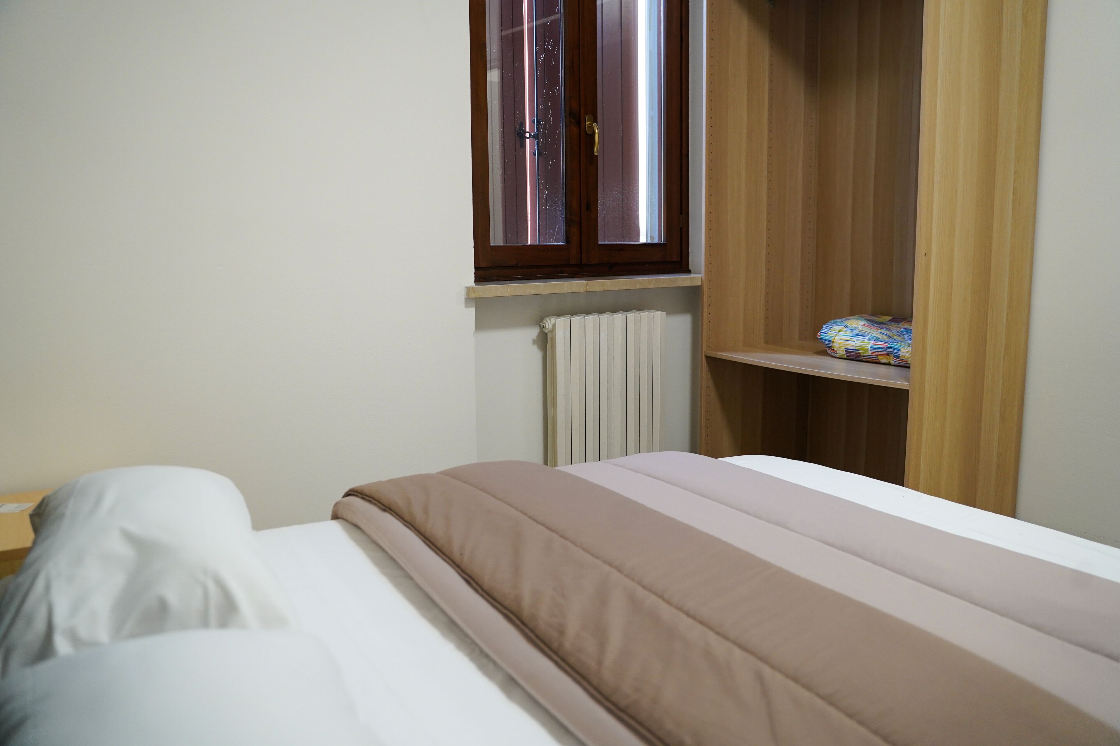 Um quarto com cama, guarda-roupa e janela.