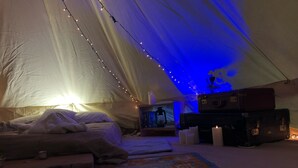 Uma tenda com uma cama, um candeeiro e malas.