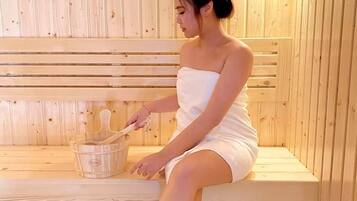 Uma pessoa sentada em uma sauna de madeira com um balde.