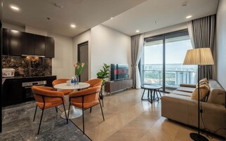 Uma sala de estar moderna com um sofá, uma mesa de jantar com cadeiras, uma televisão e uma varanda com vista.