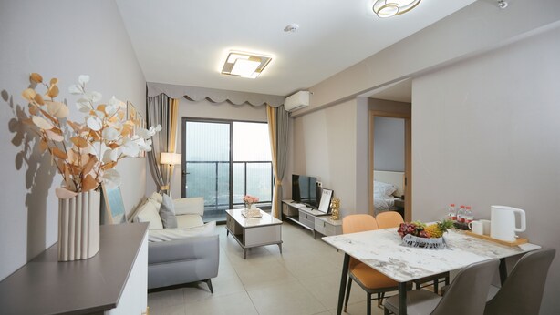 Uma sala de estar moderna com um sofá, uma mesa de jantar com cadeiras, uma televisão e uma varanda com cortinas.
