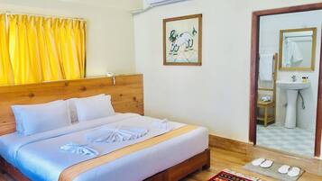 Quarto de hotel com cama de madeira, mesa de cabeceira, espelho, banheiro com pia e chuveiro, e cortina amarela.