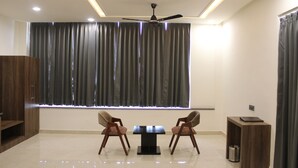 Quarto moderno com ventilador de teto, uma mesa com duas cadeiras, armário e janela com cortinas.