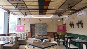 Um restaurante com cabines e mesas, ventiladores de teto e painéis decorativos na parede.