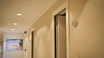 Um corredor com portas, uma placa na parede e um quadro.