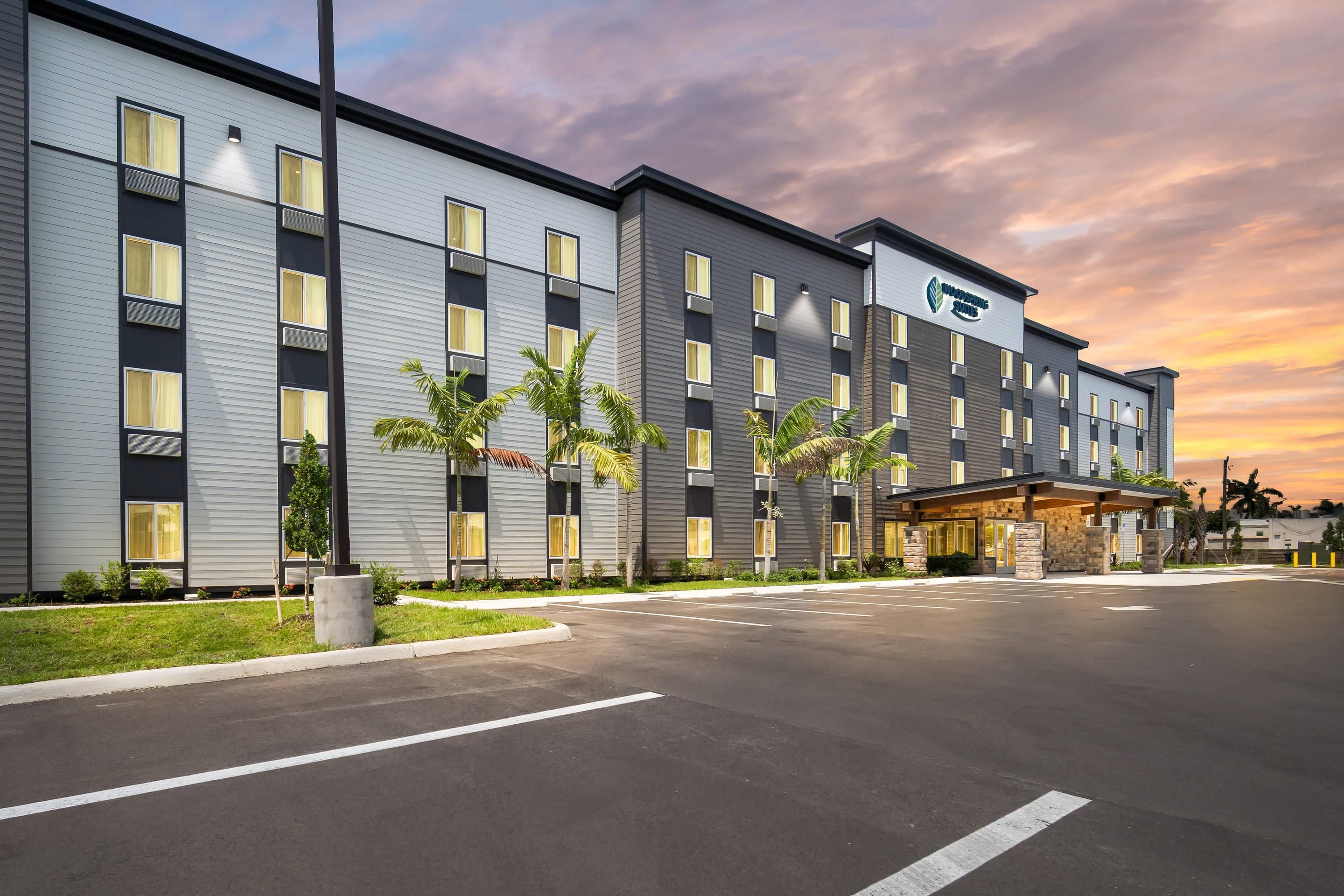 Um hotel moderno com um telhado plano, várias janelas e uma área de entrada coberta.