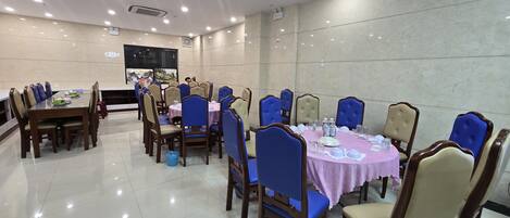 Uma sala de conferências com parede de mármore, uma tela grande e uma mesa redonda com cadeiras azuis e castanhas.