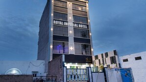 Um hotel com fachada moderna, grandes janelas e uma placa chamativa com a inscrição "ROYAL IMPERIAL HOTEL".