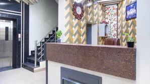 Uma área de recepção com design moderno, apresentando uma parede estampada, um relógio e um balcão de atendimento.