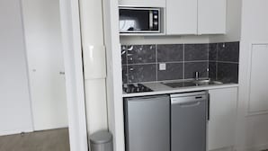 Cozinha moderna com micro-ondas, pia, lava-louças e painel de azulejos.