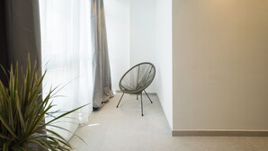 Um interior moderno com uma cadeira, uma planta e uma janela com cortinas.
