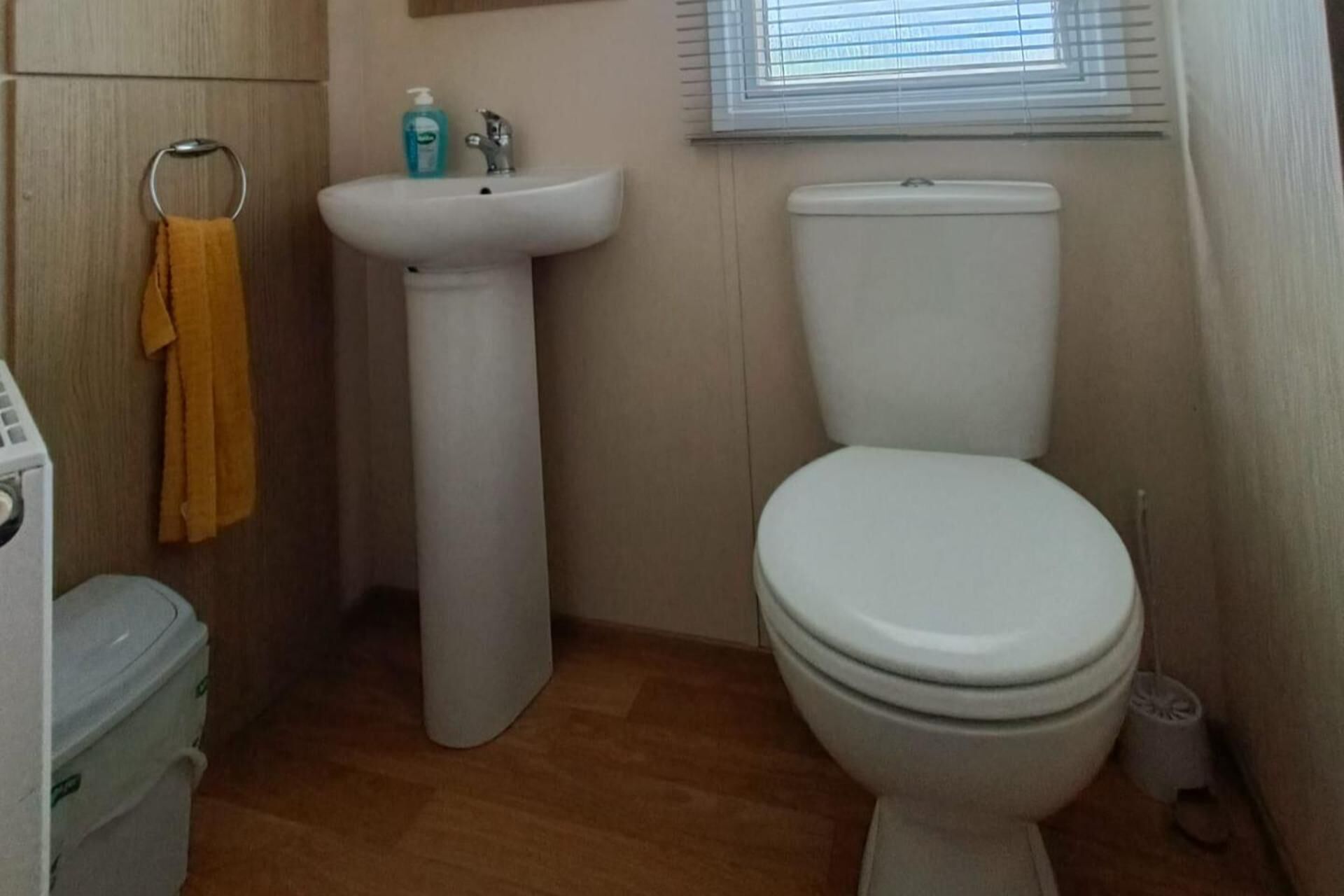 Um banheiro pequeno com pia de pedestal, vaso sanitário e porta-toalhas.