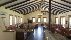 Uma sala de estar ampla com vários sofás e poltronas, televisão e lareira de pedra.