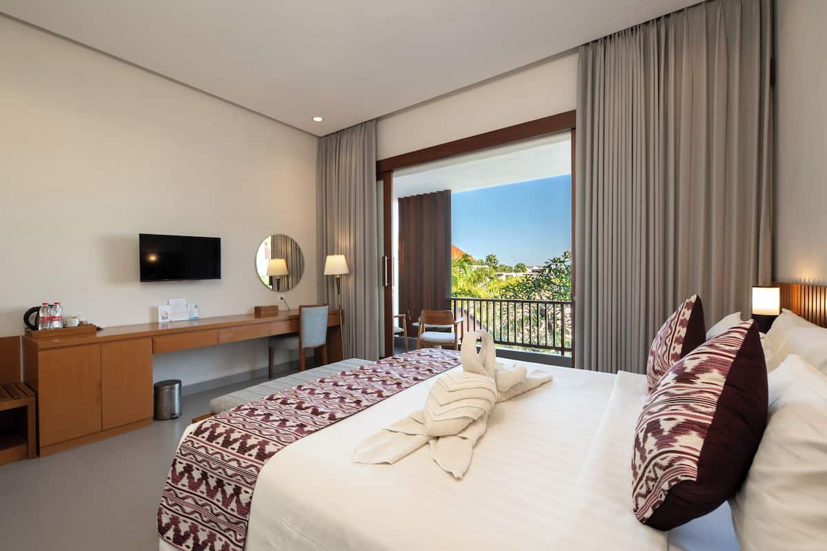 Quarto de hotel com cama, escrivaninha, televisão, varanda e vista, e janela com cortinas.