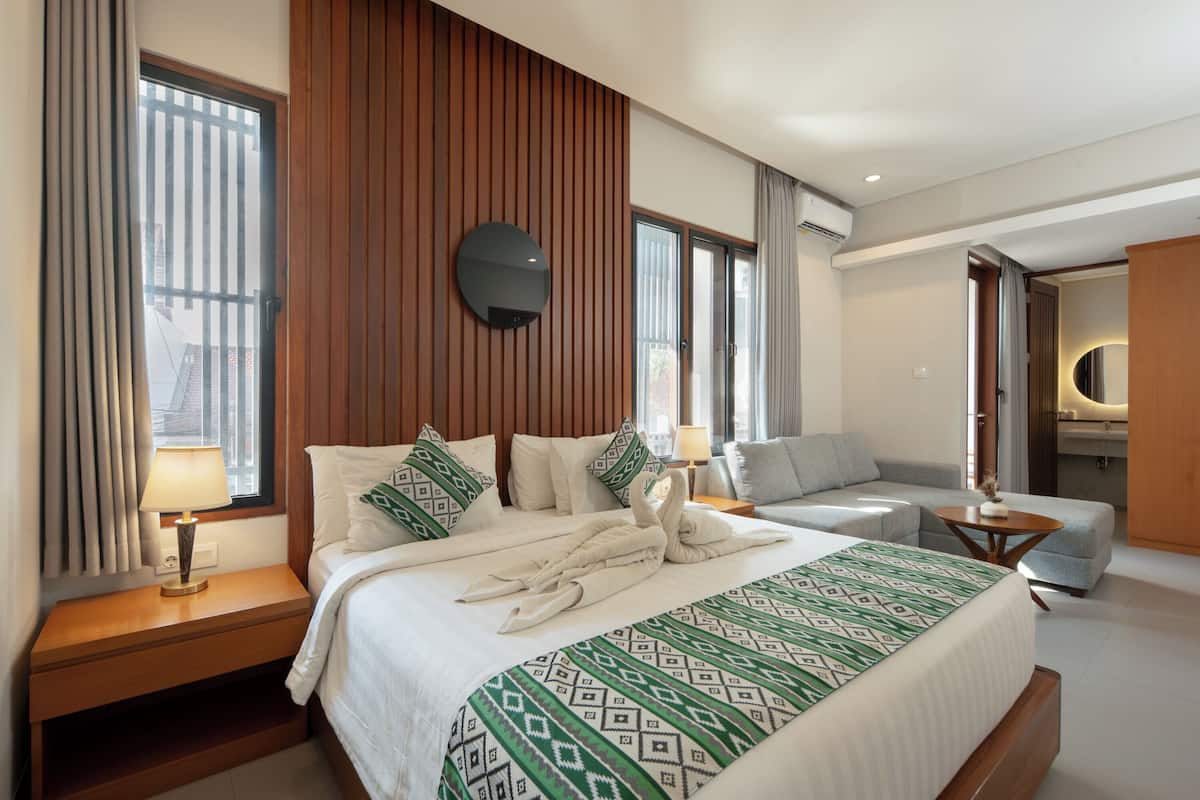 Quarto de hotel com uma cama grande, um sofá, uma mesa redonda e um espelho.