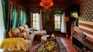 Interior acolhedor de uma cabana, com um sofá, uma mesa com velas, um ventilador e uma parede decorada com estrelas.